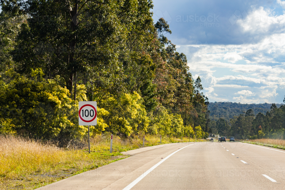 Image of 100 speed zone sign beside Australin road with flowering ...