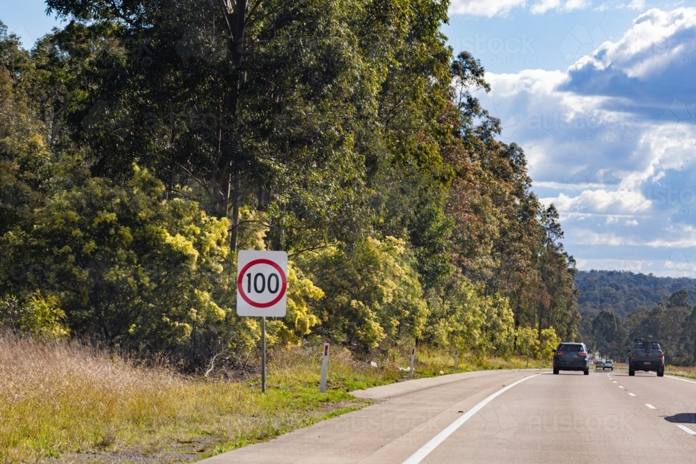 Image of 100 speed zone sign beside Australin road with flowering ...