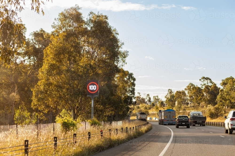 Image of 100 speed zone sign beside highway with trucks and cars ...