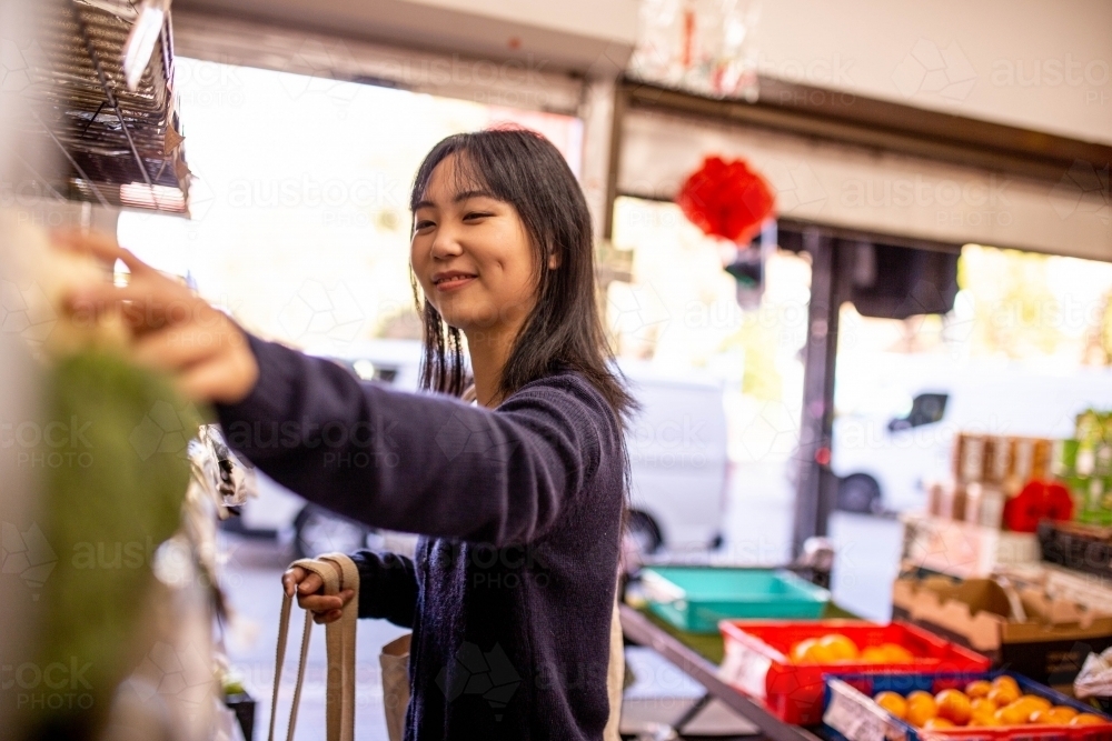 Image of 20-something Asian woman shopping buying groceries at a ...