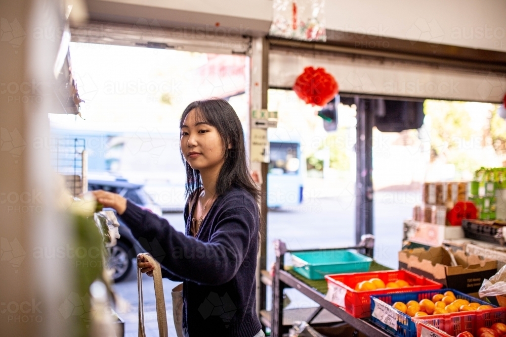 Image of 20-something Asian woman shopping buying groceries at a ...