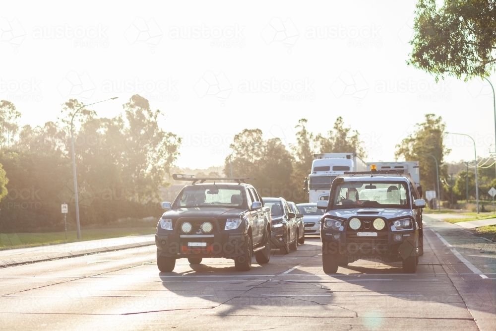 Image of 4x4 car and ute stopped at traffic light intersection backlit ...