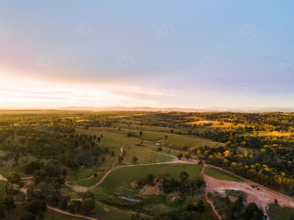 Image of 4x4 tracks winding through paddock at sunset - Austockphoto