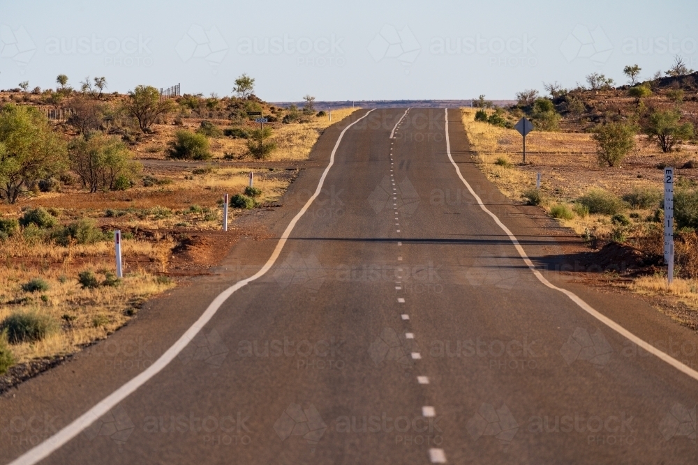 Image of A bitumen road running towards the horizon through an arid ...
