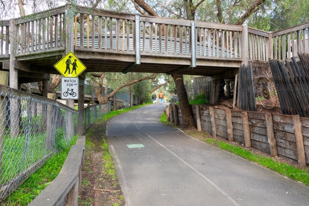 Image of A bitumen walking track going under an overhead wooden ...