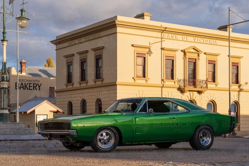 Image of A brightly coloured muscle driving past and historic bank ...