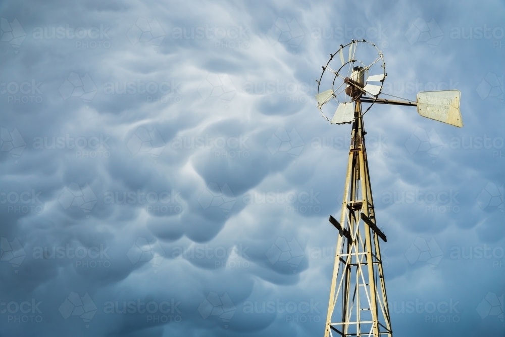 Image of A broken windmill with dark mammatus clouds above - Austockphoto