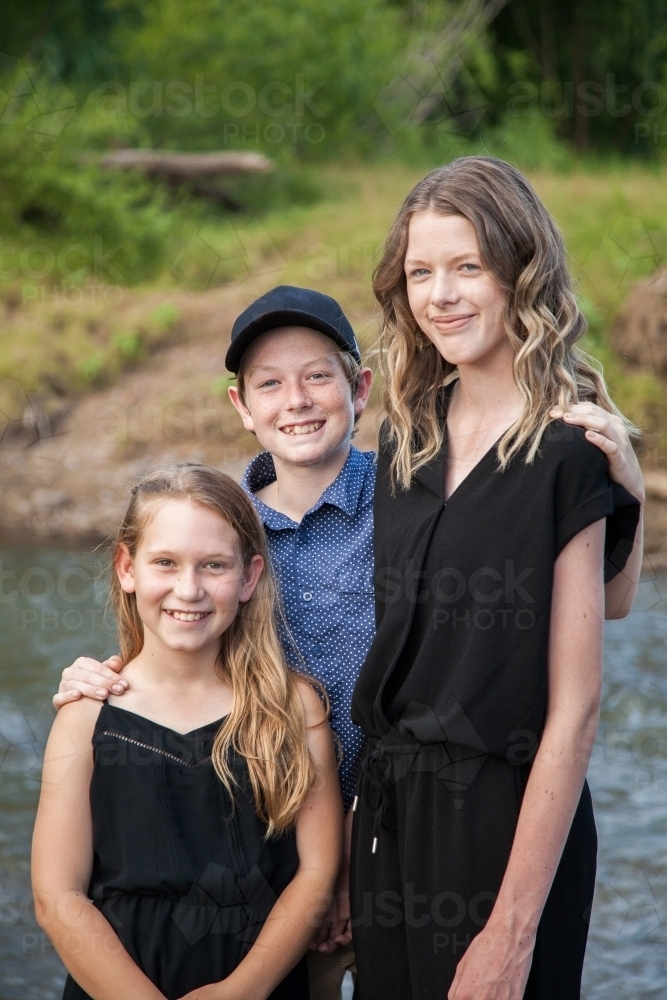 Image of A brother and two sisters together by the riverside - Austockphoto