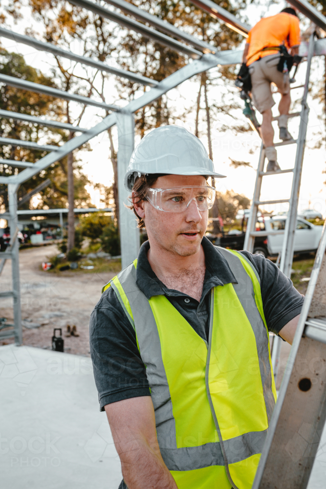 Image of A builder holding a steel ladder at the building site ...