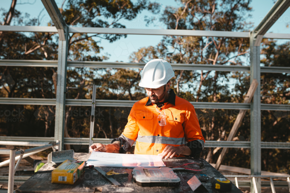 Image of A builder looking at blueprints on construction build worksite ...