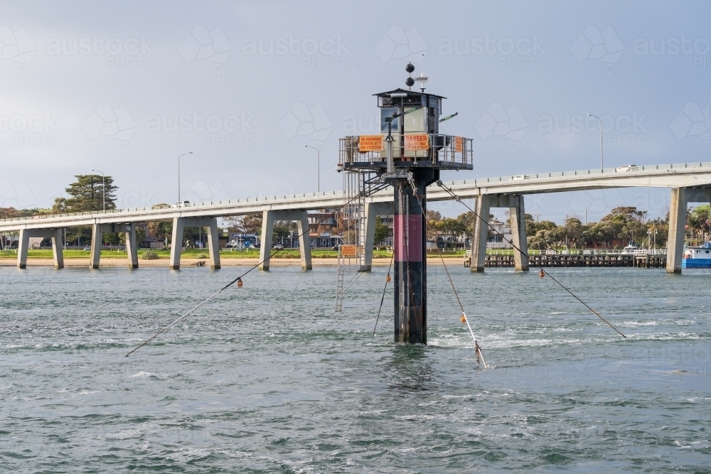 Image of A coastal beacon supported by cables rising out of rough water ...