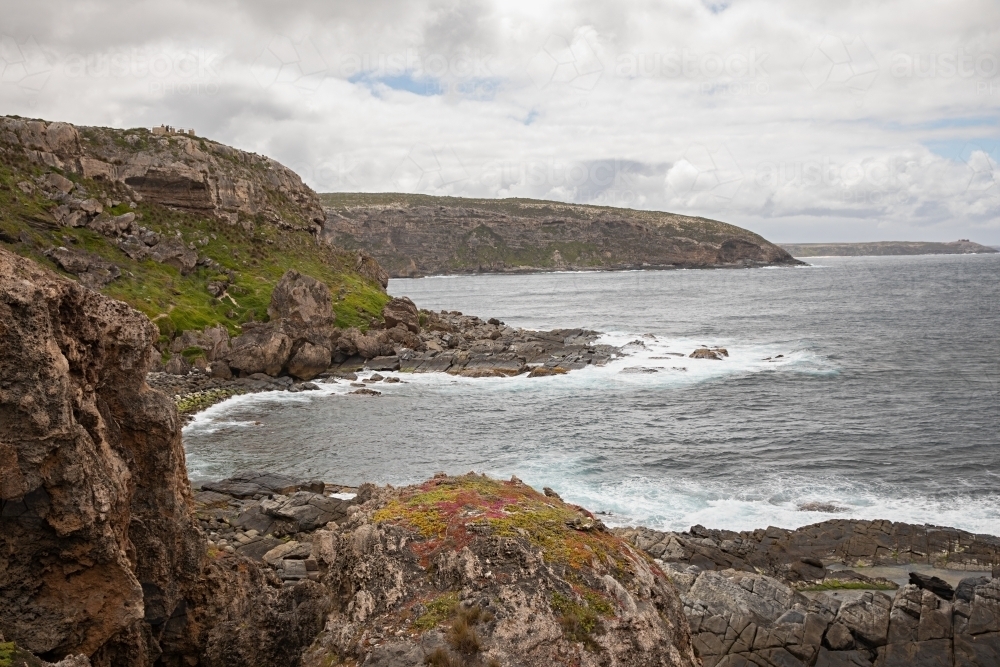 Image of A coastal cliff with ragged waters and jagged rocks - Austockphoto