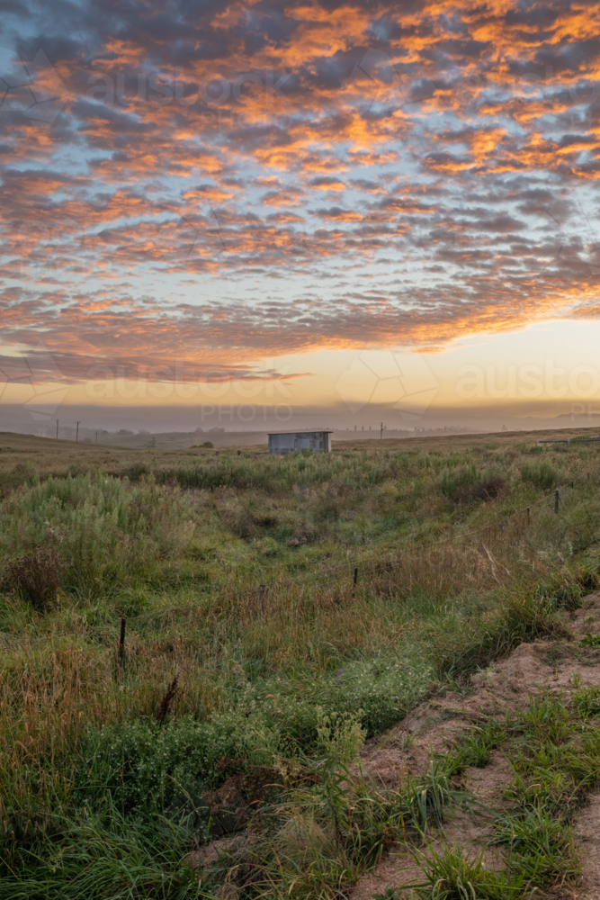 Image of A colourful dawn sky over a country field - Austockphoto