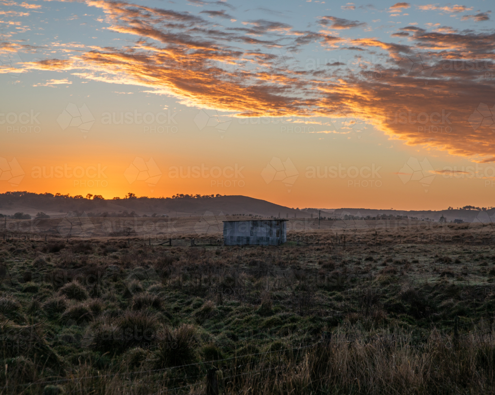 Image of A colourful dawn sky over a country field - Austockphoto