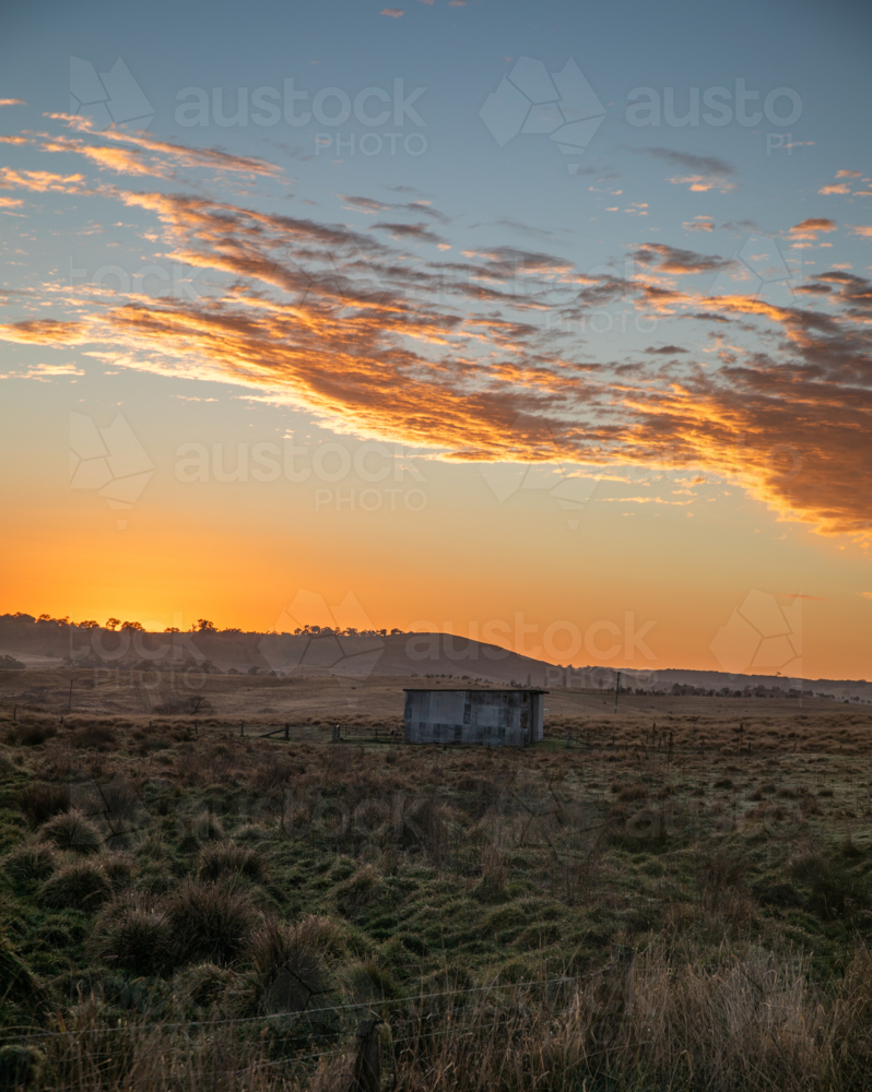 Image of A colourful dawn sky over a country field - Austockphoto