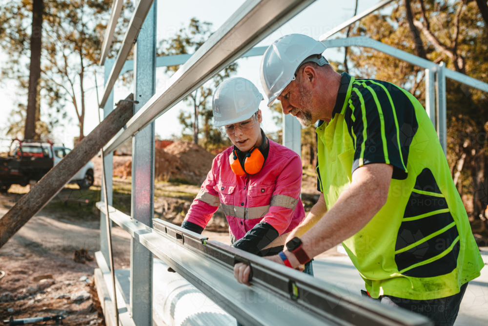 Image of A contractor teaching a young apprentice how to use the ...
