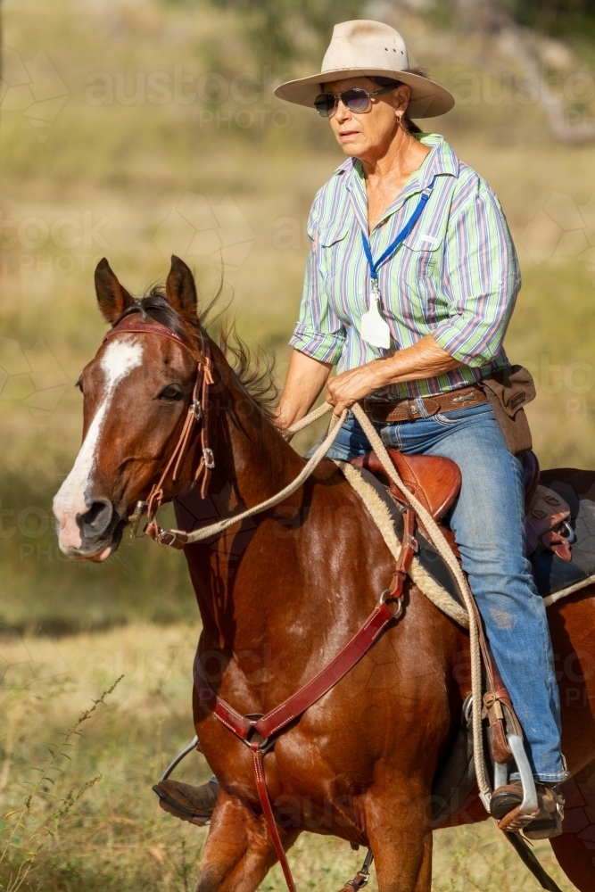 Image of A country lady in her sixties riding a horse. - Austockphoto