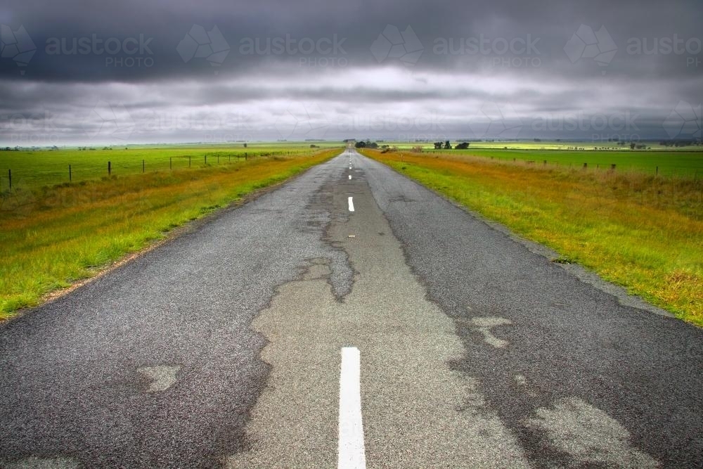 Image of A country road leading into bad weather - Austockphoto