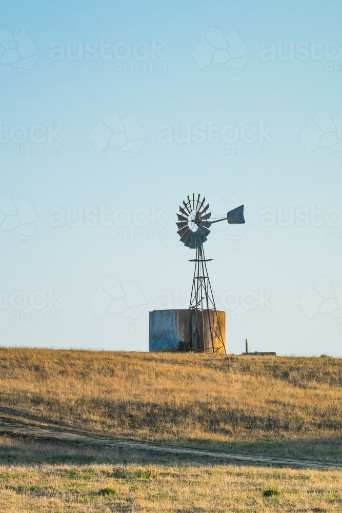 Image of A country windmill and water tank on a hill - Austockphoto