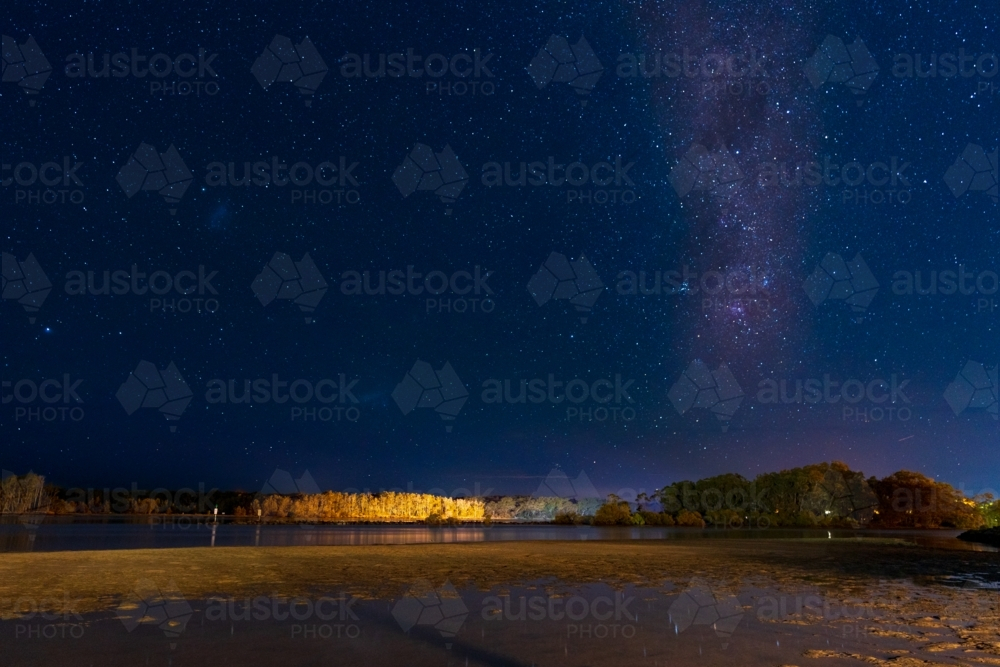 Image of A dark starry night sky over a coastal inlet and mangroves ...