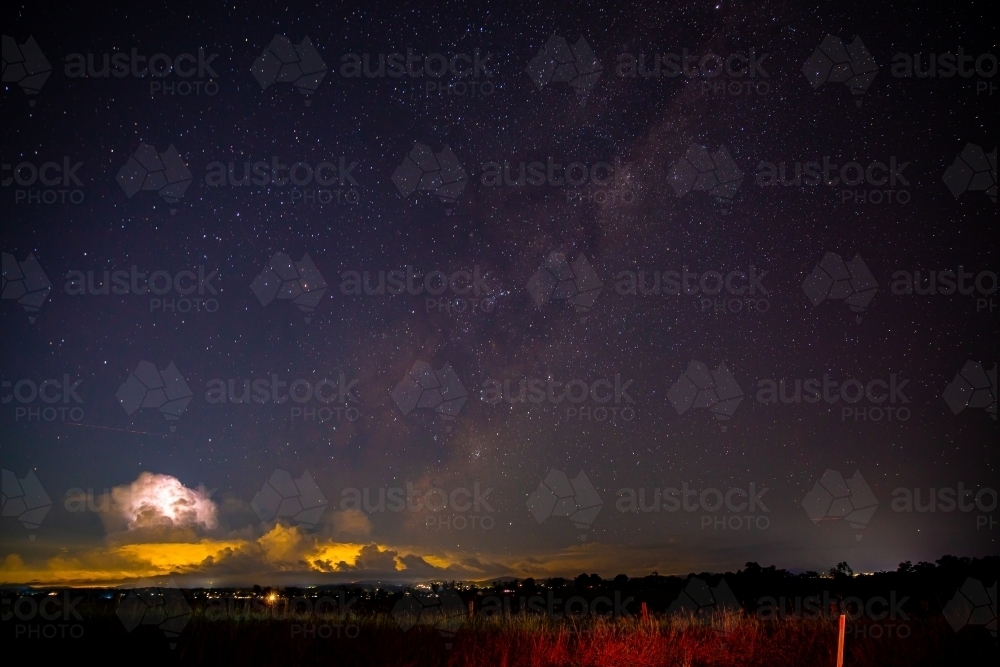 Image of a distant storm cloud against a clear night sky full of stars ...