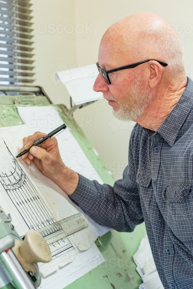 Image of A draftsman wearing glasses sketching a design on a drawing ...