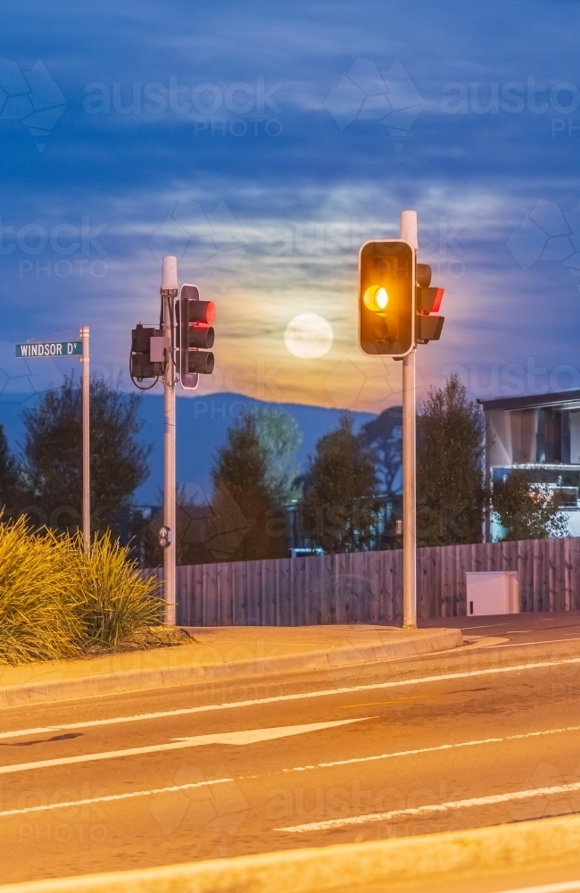 Image of A full moon rising between traffic lights at an intersection ...