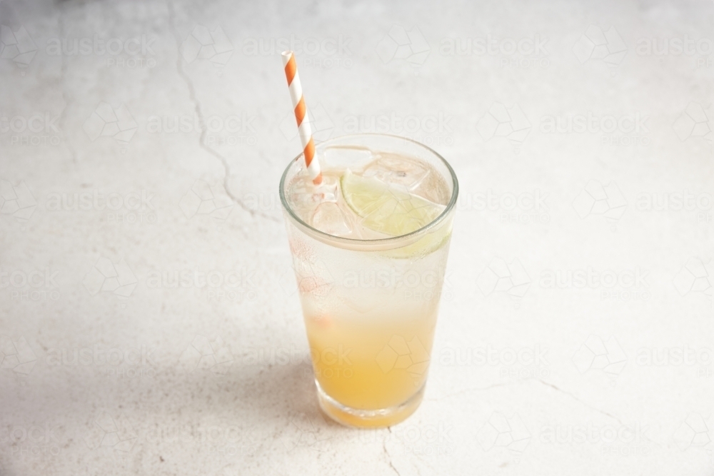 Image of A glass of yellow soda with red and white striped straw ...