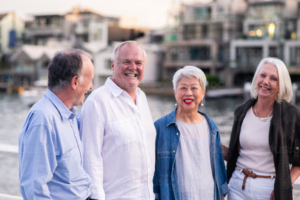Image of A group of four happy seniors in a coastal setting - Austockphoto