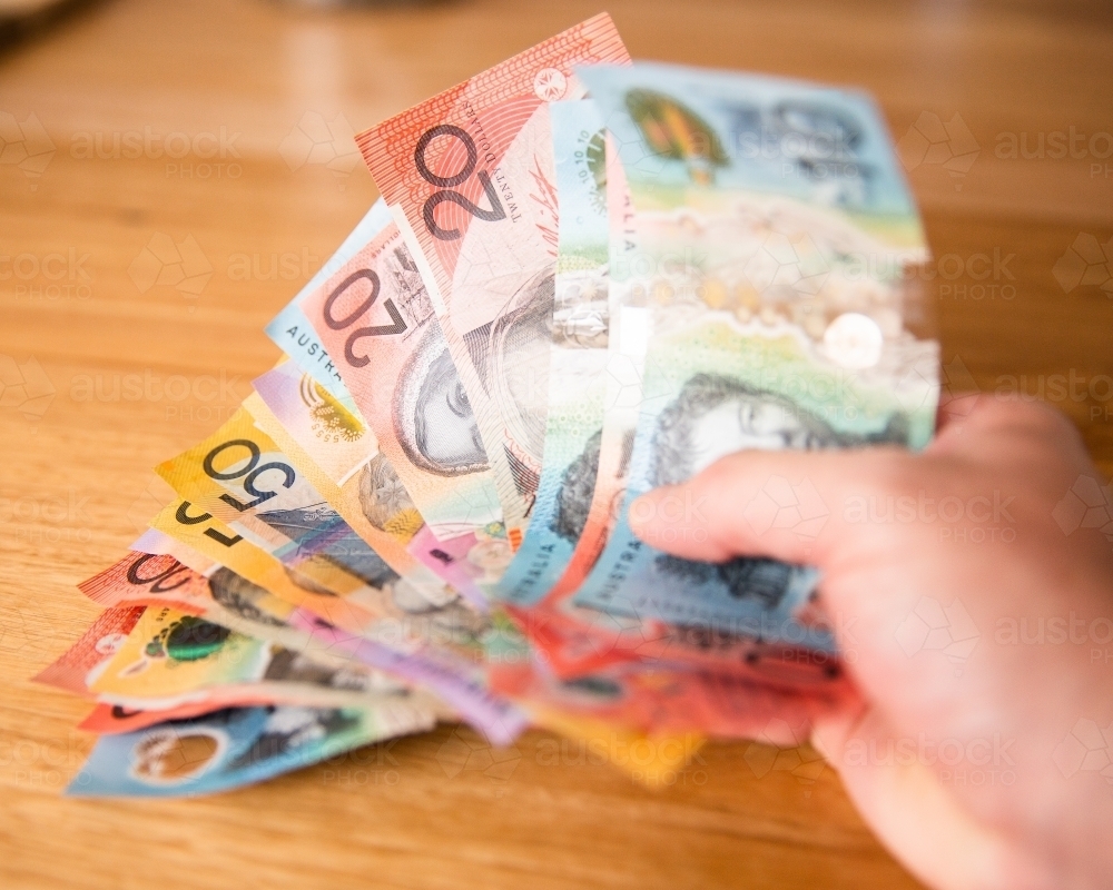 Image of a hand holding Australian cash in bank notes - Austockphoto