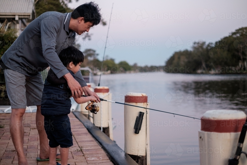 Image of a kid being taught how to fish - Austockphoto