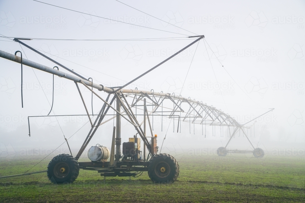 Image of A large irrigation sprinkler in a paddock on a foggy morning ...