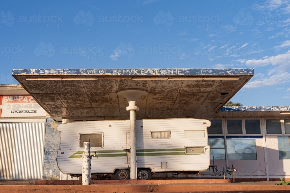 Image of A large retro style caravan parked under the canopy of an ...