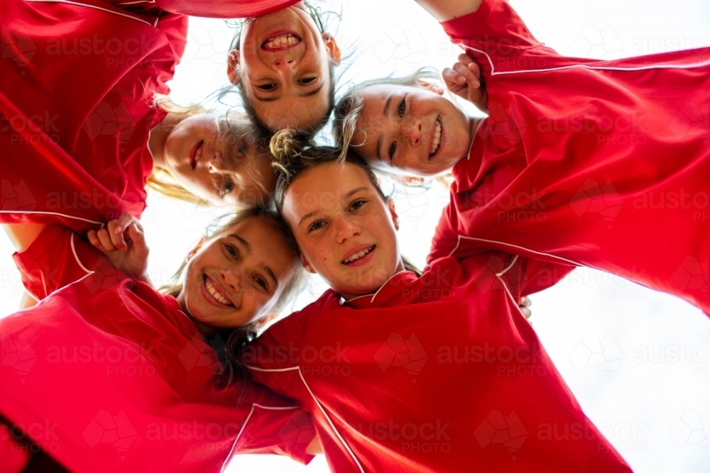 Image of A looking up view of tween girls football team in a huddle ...