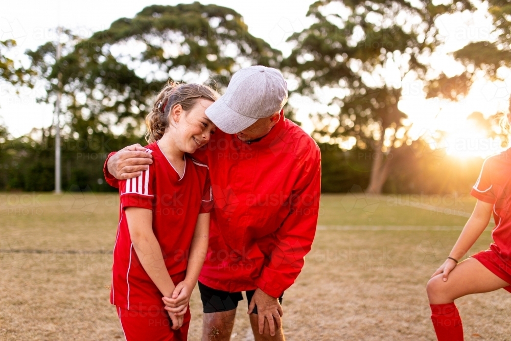 Image of A male football coach with his arm around a player encouraging ...