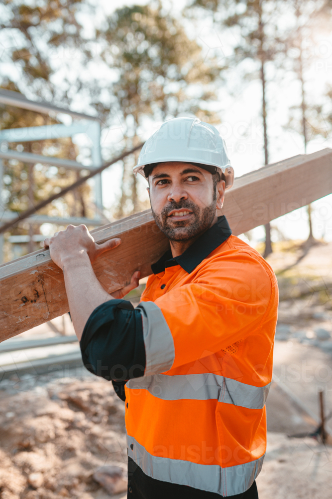 Image of A man carrying a piece of lumber on his shoulder at a ...