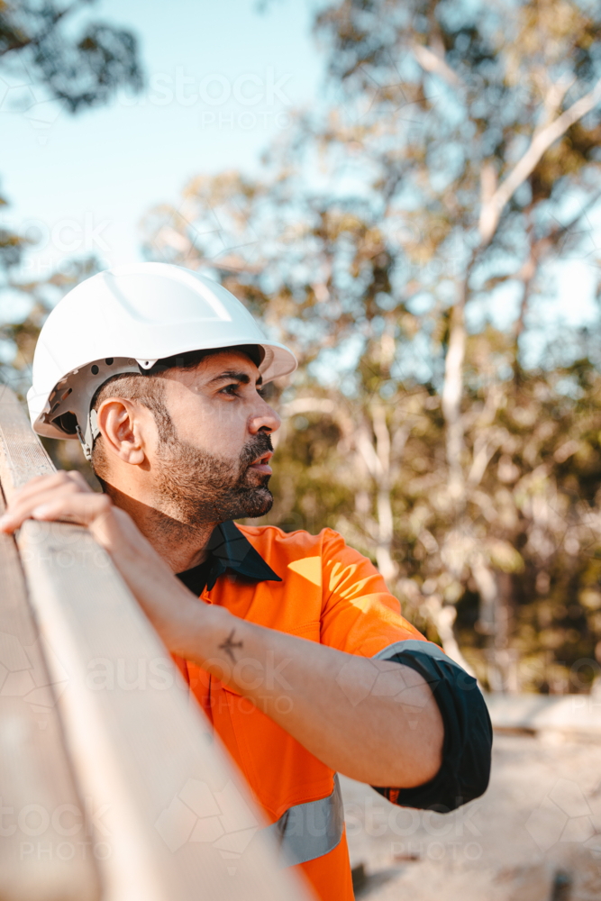 Image of A man carrying a piece of lumber on his shoulder at a ...