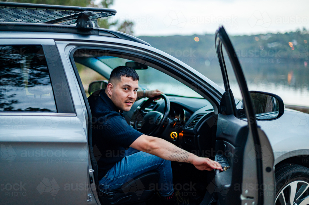 Image of A man in his thirties smiles as he relaxes in his car by a ...