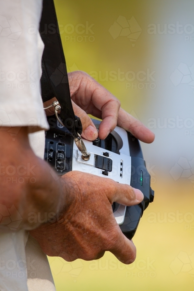 Image of A man operating a remote control for a toy boat. - Austockphoto