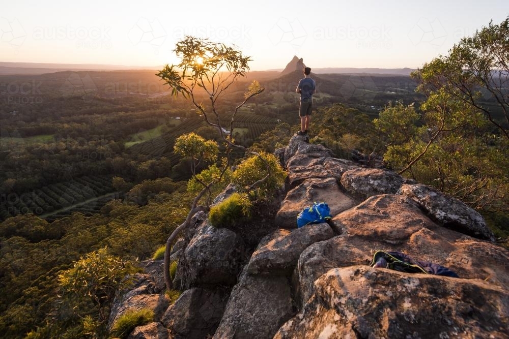 Image of A man overlooking a view from a rocky lookout - Austockphoto