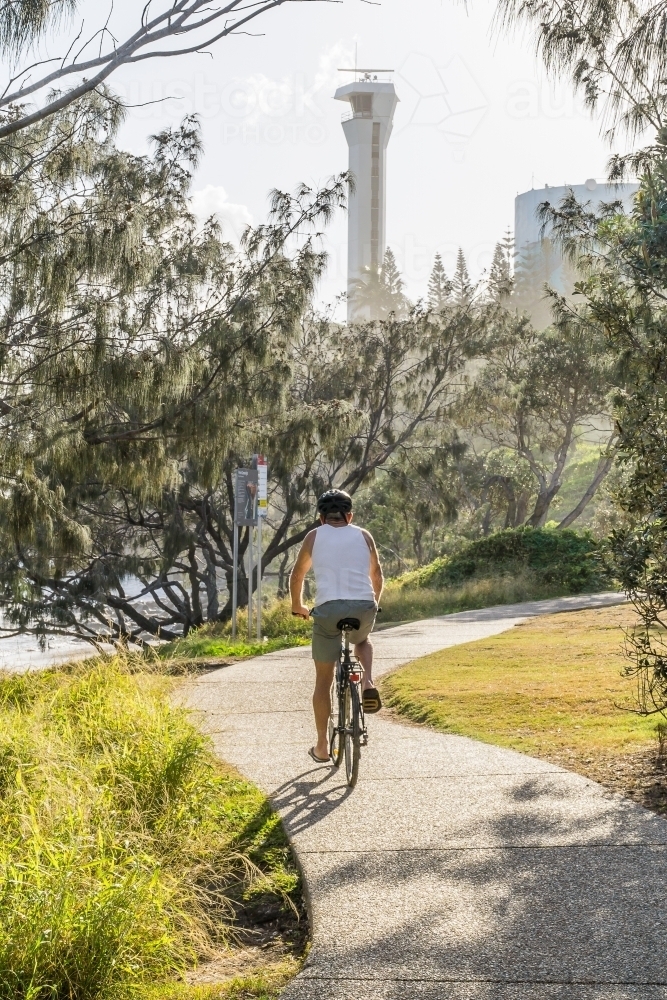 Image of A man riding a bike along a path beneath a lighthouse ...