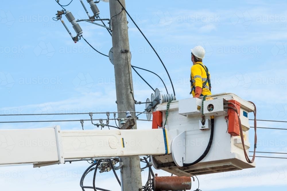 Image of A man working on power lines from a cherry picker - Austockphoto