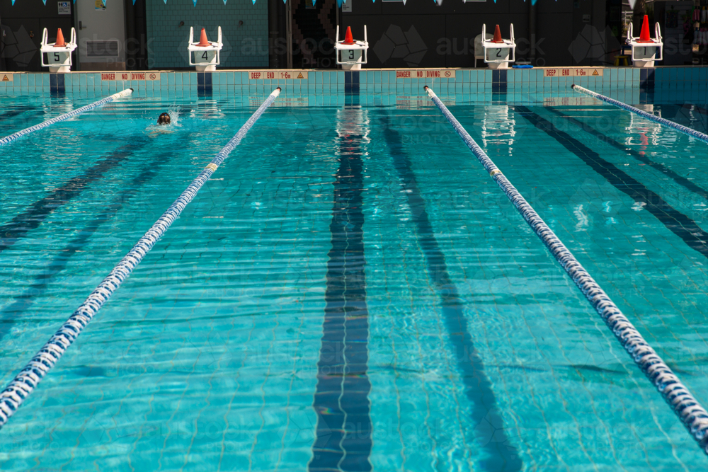 Image of a mostly empty public swimming pool except for one person on a ...