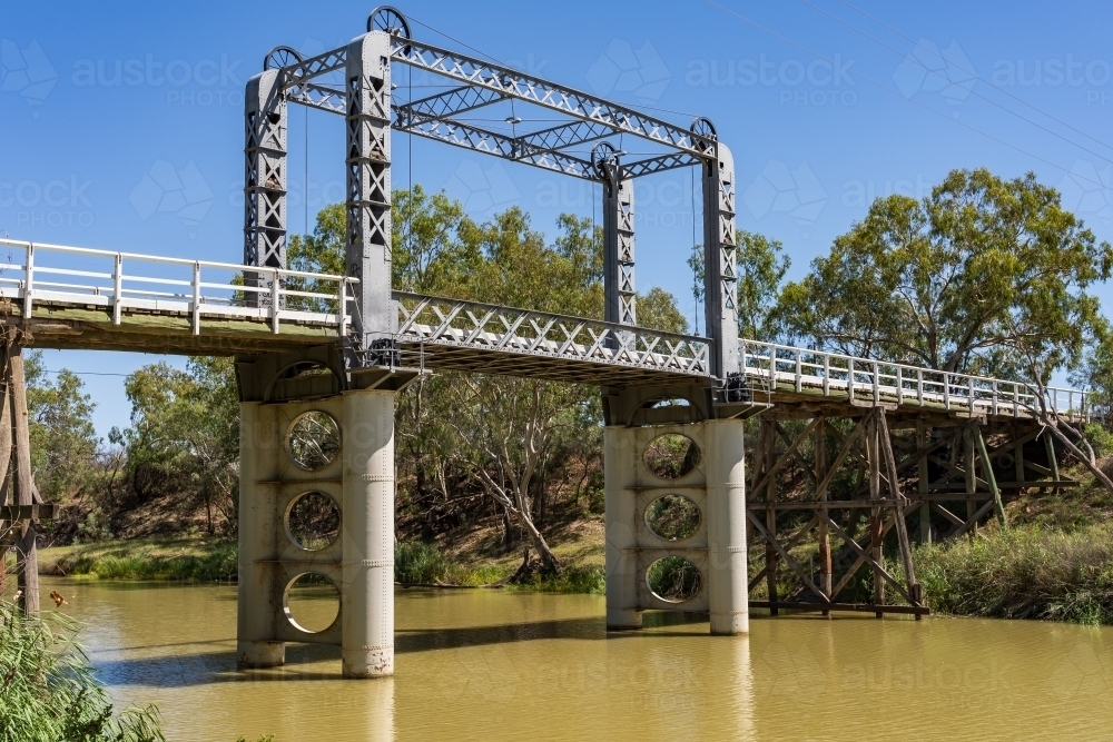 Image of A murky river flowing under a disused lift span bridge ...