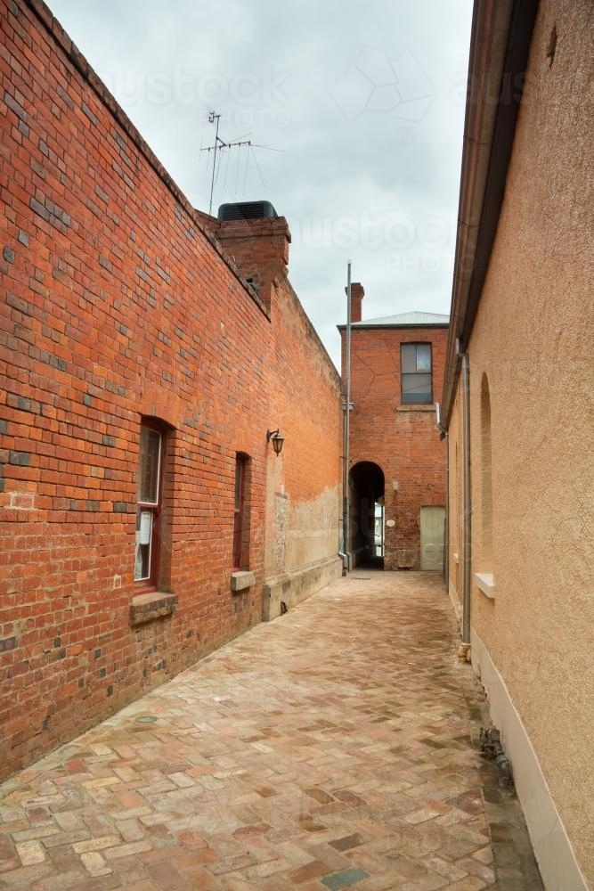 Image of A narrow lane between brick walls - Austockphoto