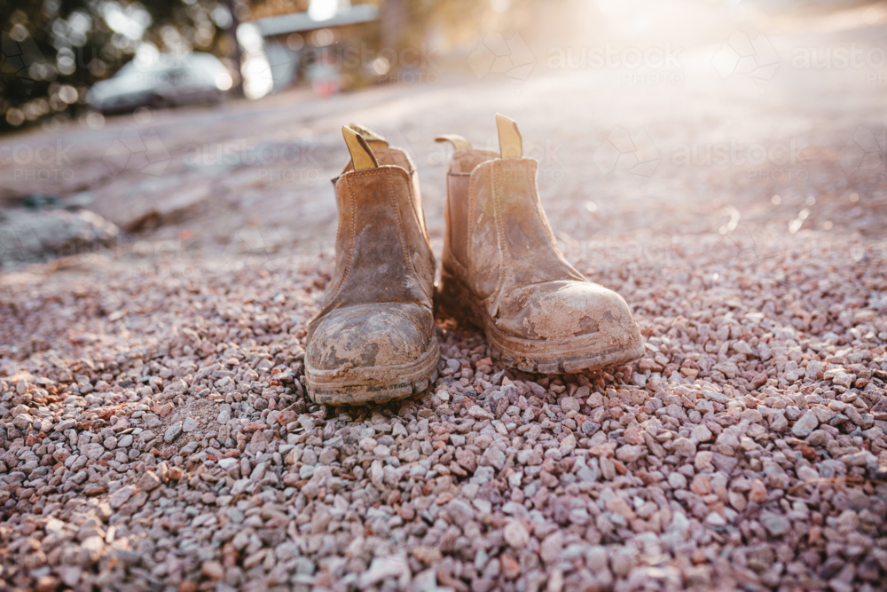 Image of A pair of worn brown boots placed on a ground covered with ...