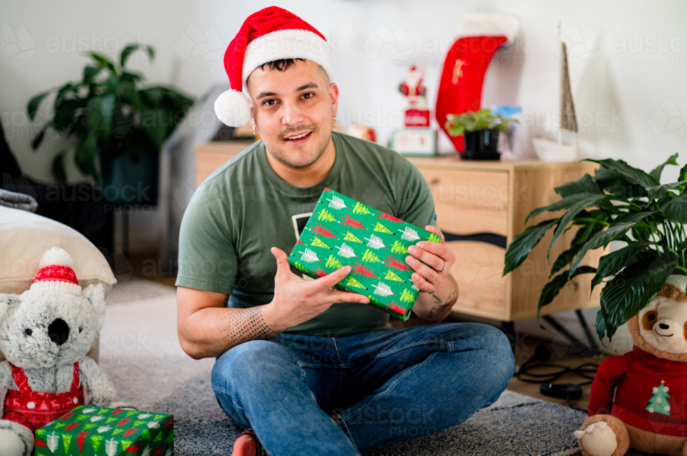 Image of A person in a Santa hat holds a wrapped gift amid Christmas ...