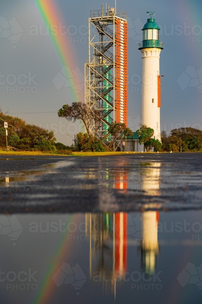 Image of A rainbow arching over a lighthouse and signal towers with ...