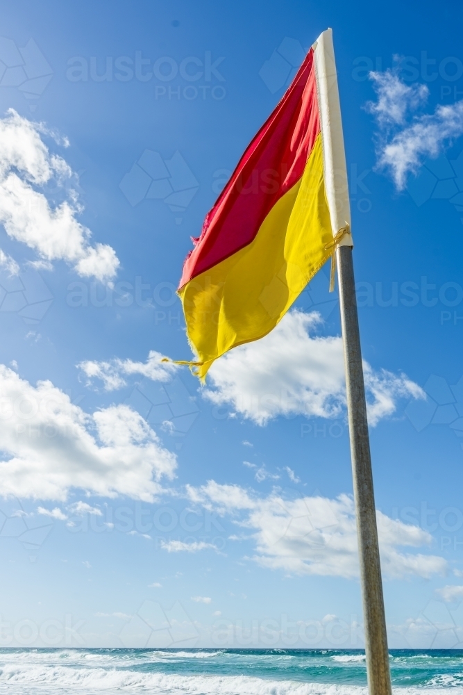 Image of A red and yellow lifesaver's flag in front of a blue sky ...