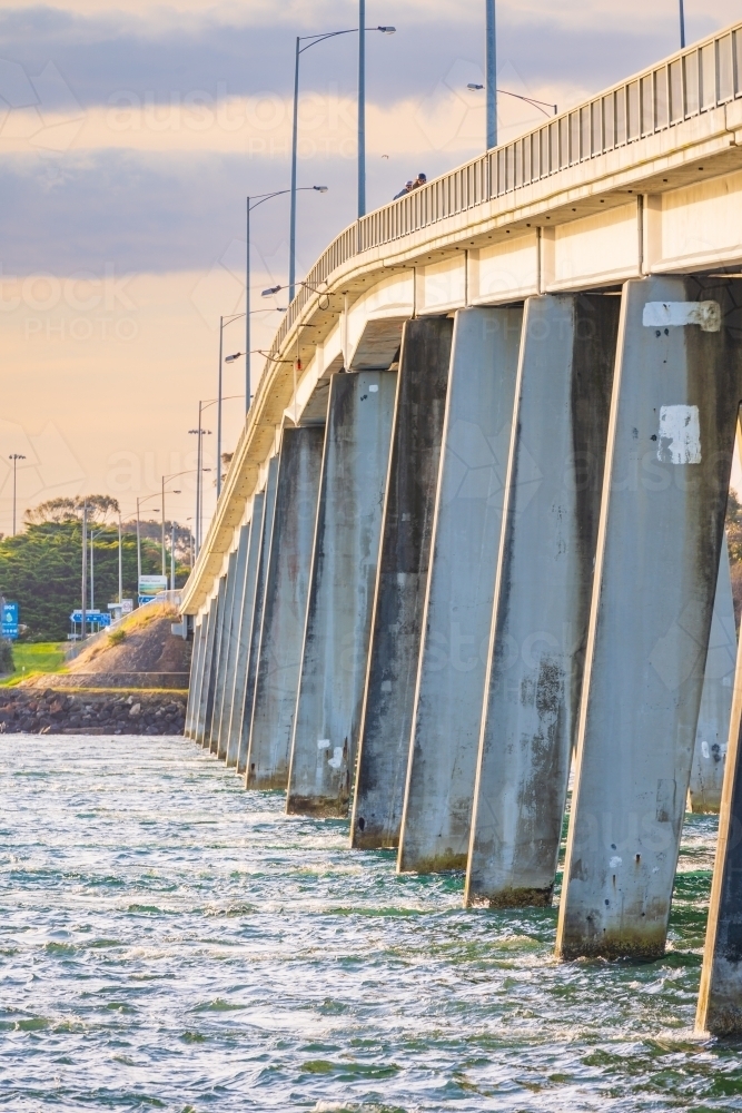 Image of A row of concrete pylons supporting a long bridge over a ...